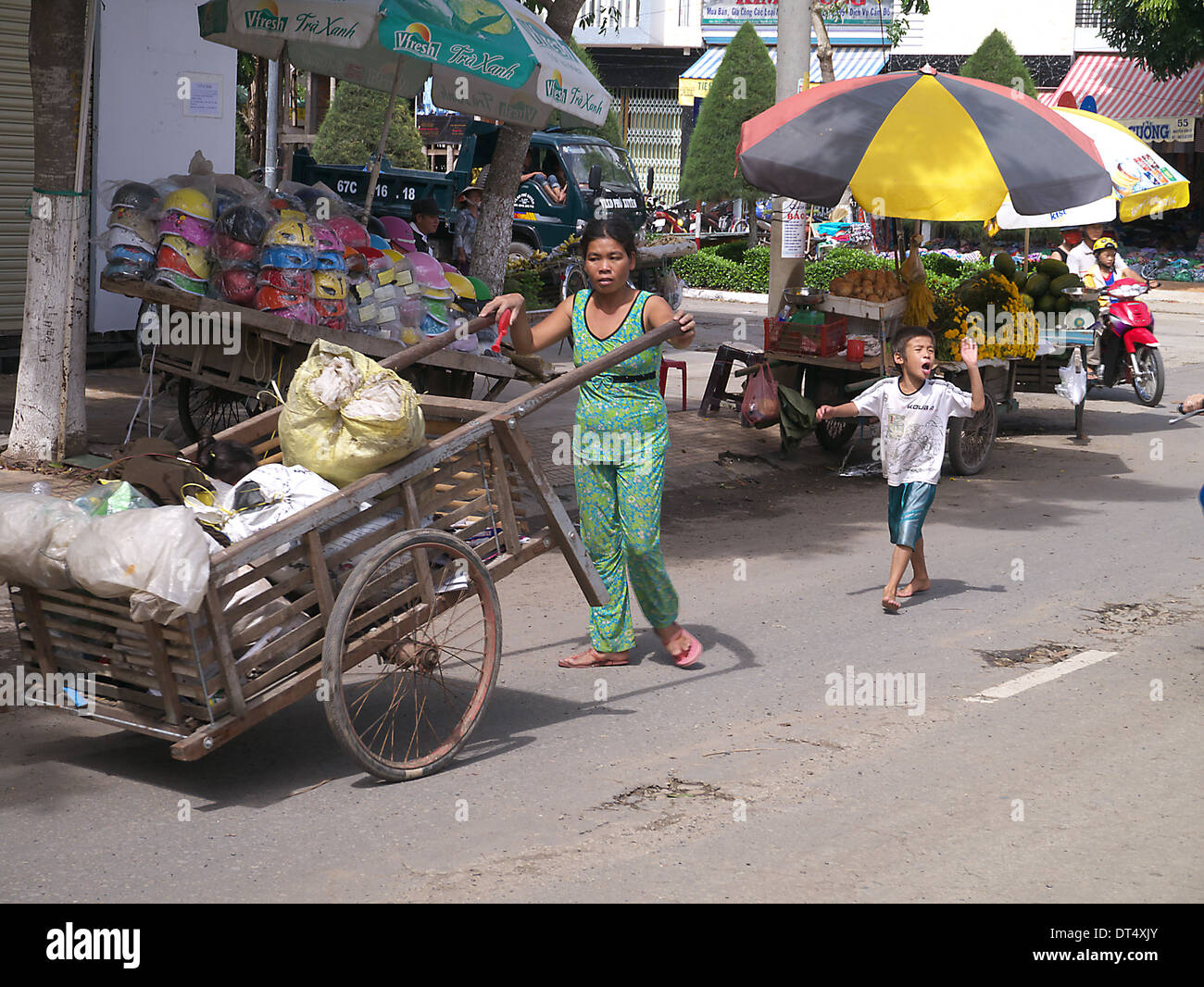 Street vendor with child walking down street in Phnom Penh Cambodia ...