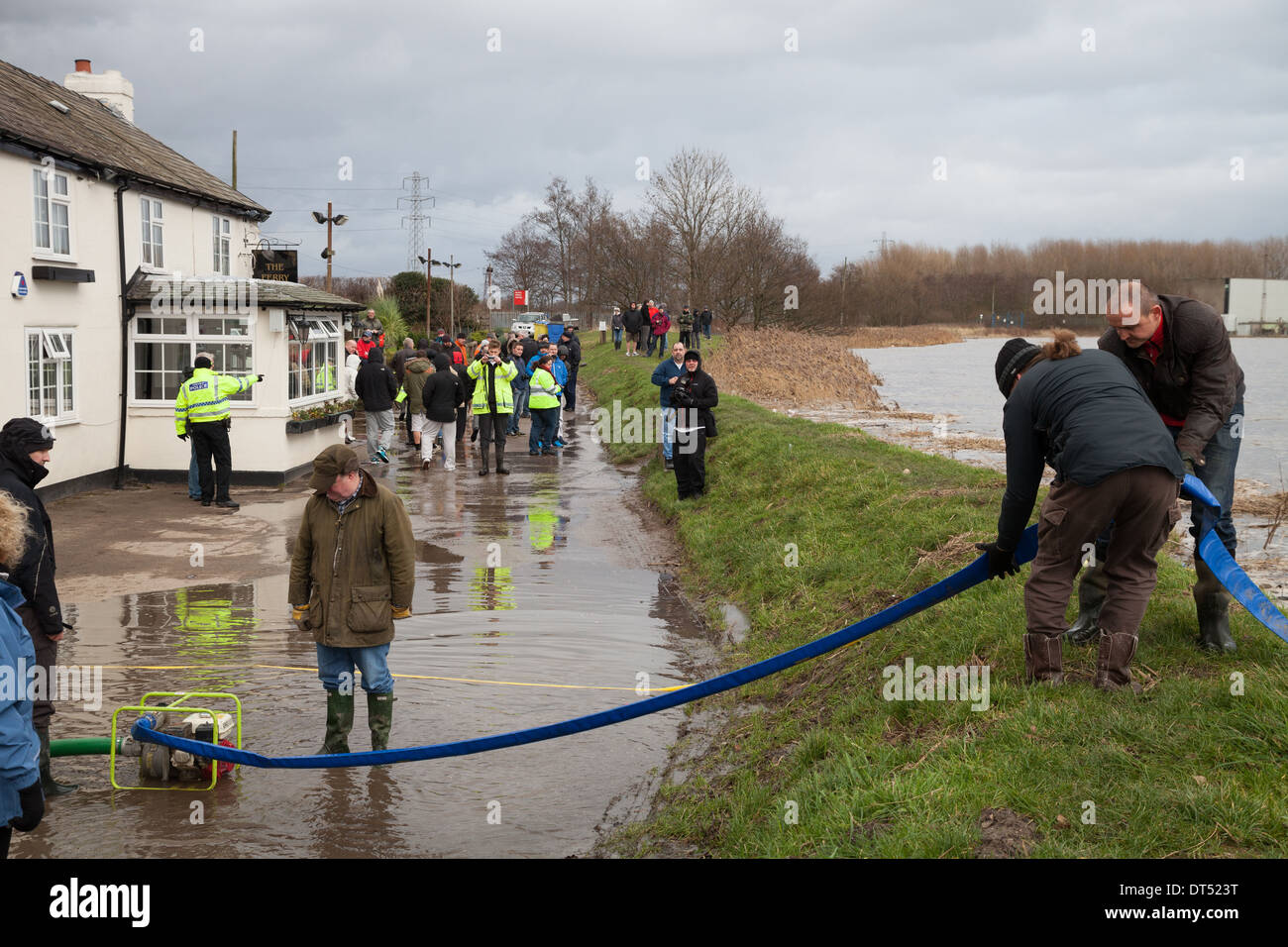 Police keep onlookers back as water is pumped from the Ferry Tavern pub ...