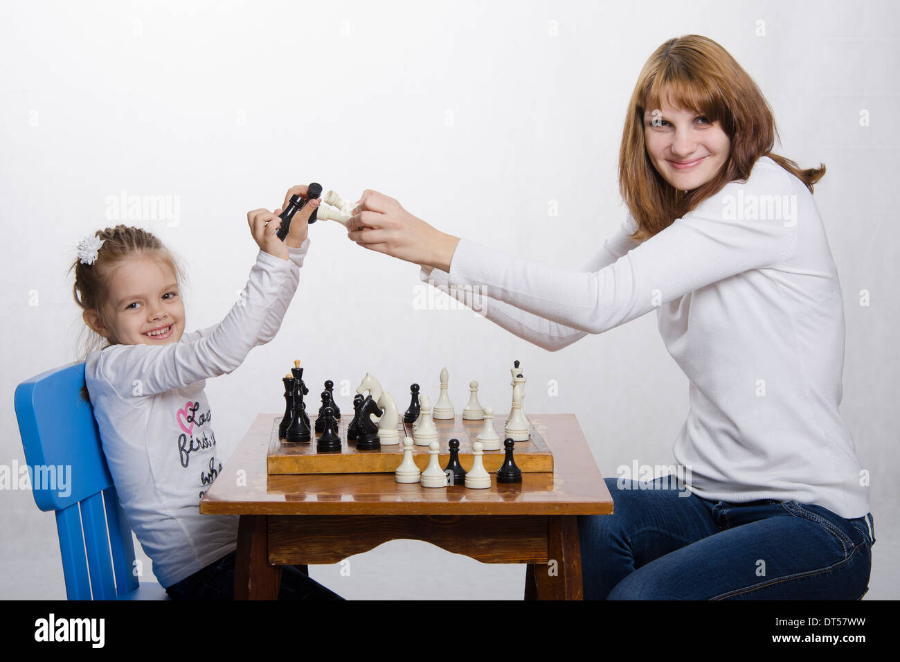 Mom and daughter playing at a table in chess. Mother teaches daughter ...