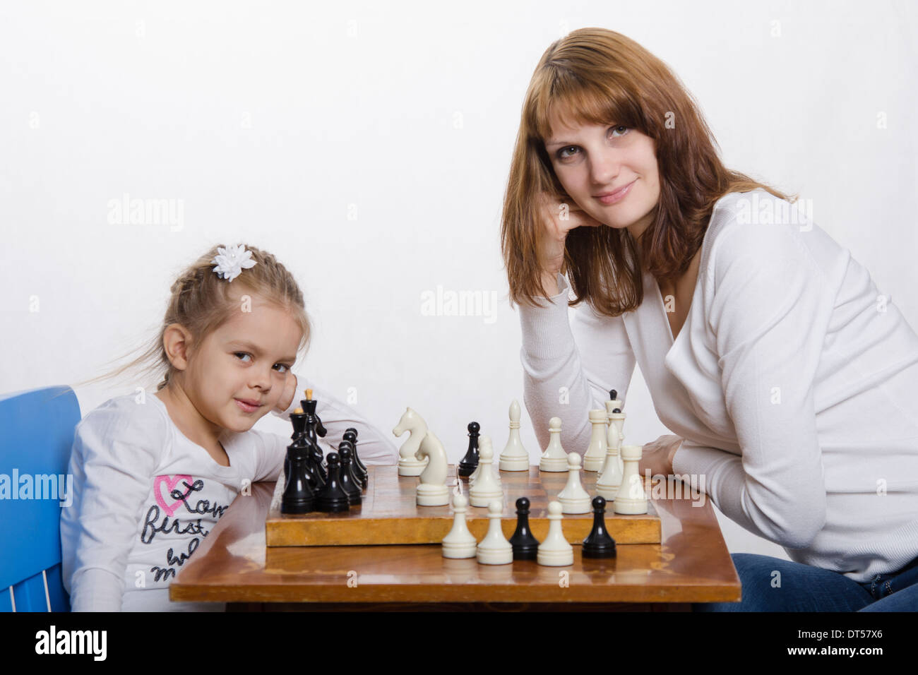 Mom and daughter playing at a table in chess. Mother teaches daughter ...