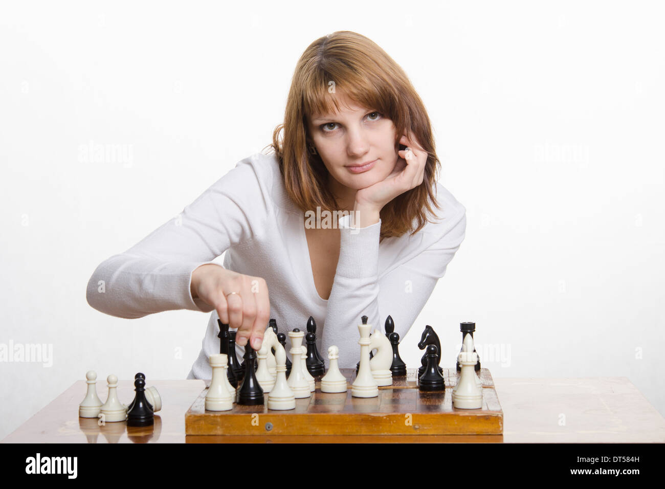 Young girl playing chess. Girl walks figure and looks into the frame ...