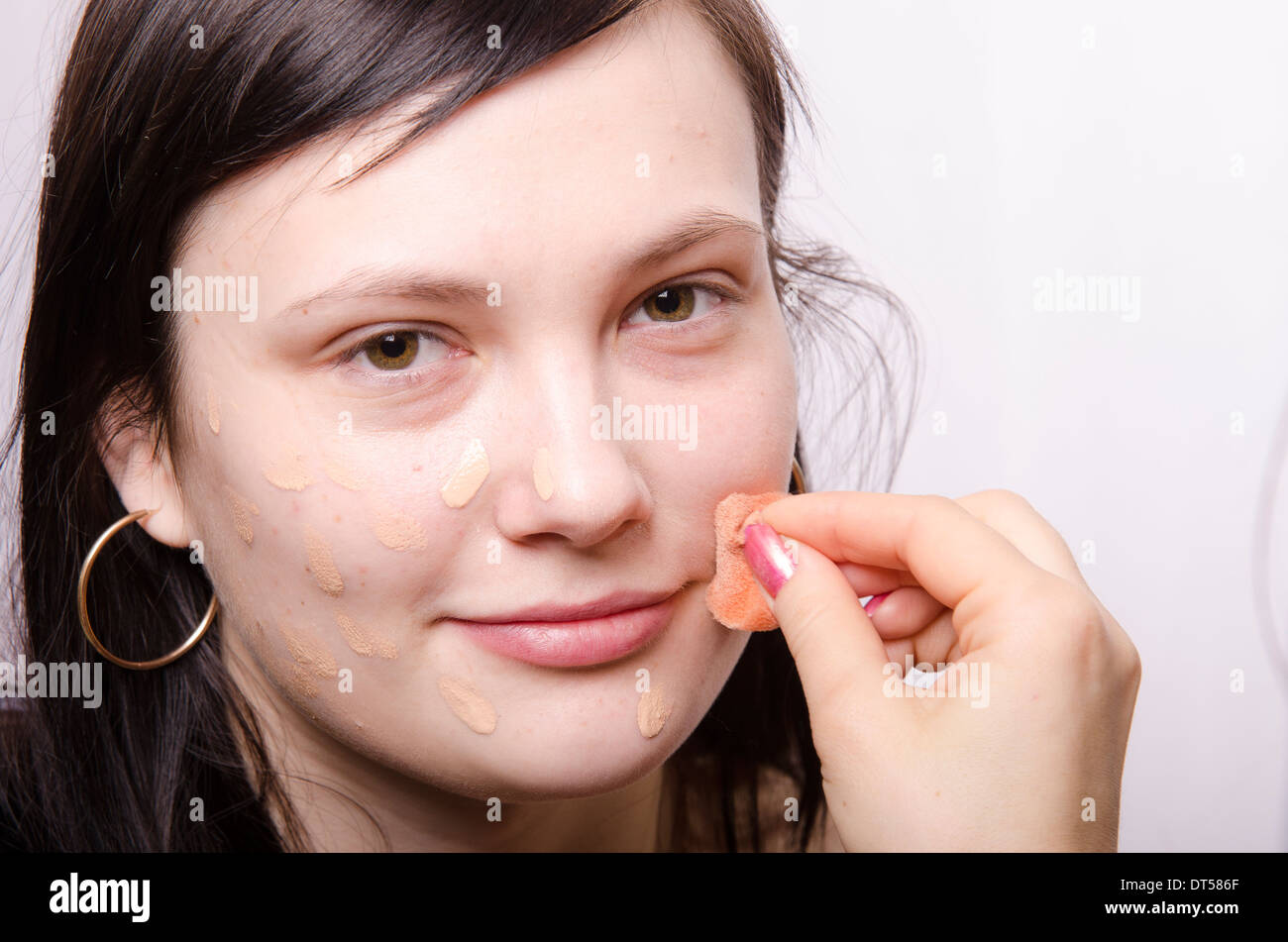 Makeup artist puts makeup model. She pointwise causes Foundation on the ...