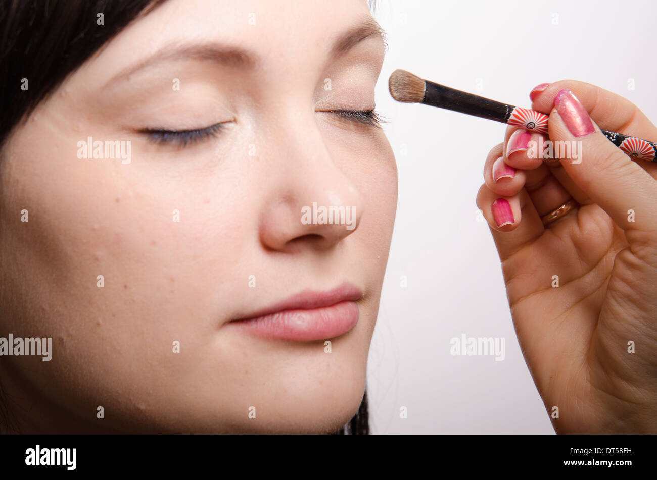 Makeup artist deals makeup on the model's face. She paints the shadows ...