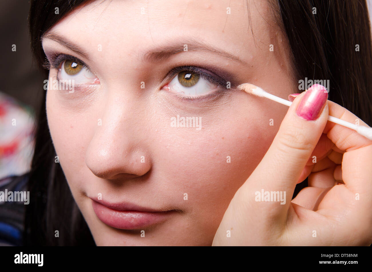 Makeup artist deals makeup on the model's face. She paints the shadows ...
