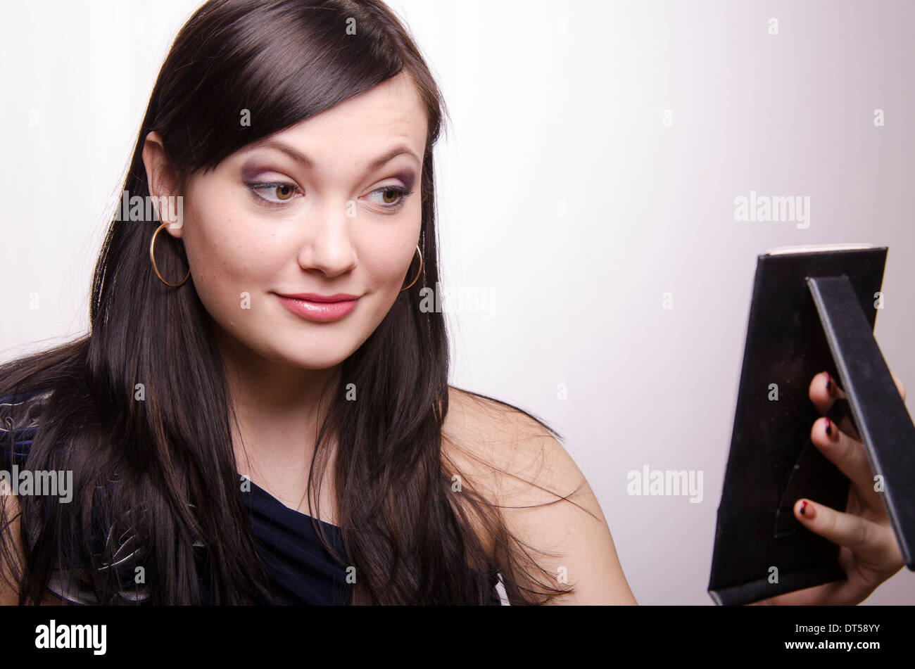 A beautiful young girl looks in the mirror. The girl is very happy with ...