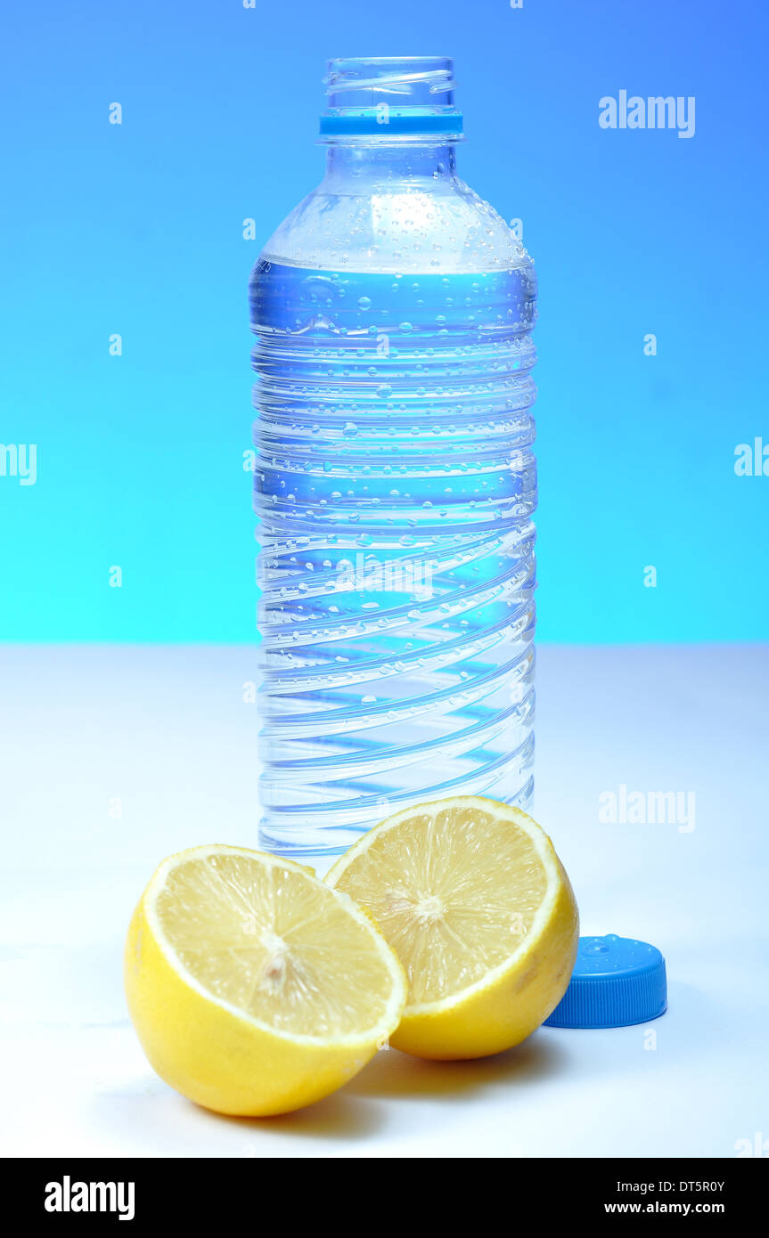 Water bottle and lemon against blue background Stock Photo - Alamy