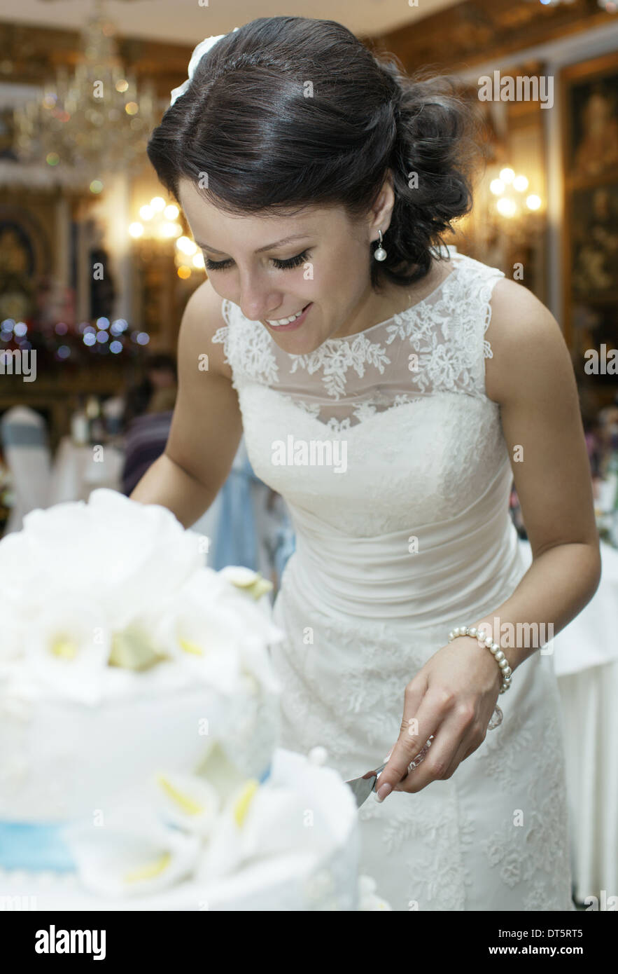 Smiling beautiful bride cutting the wedding cake Stock Photo - Alamy