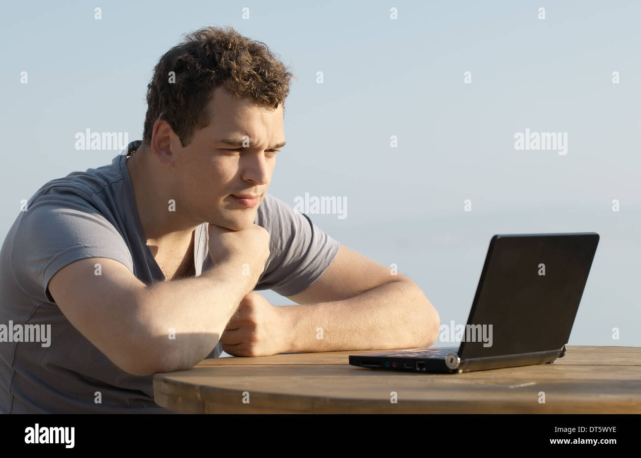 Man looking to the display of small laptop computer Stock Photo - Alamy