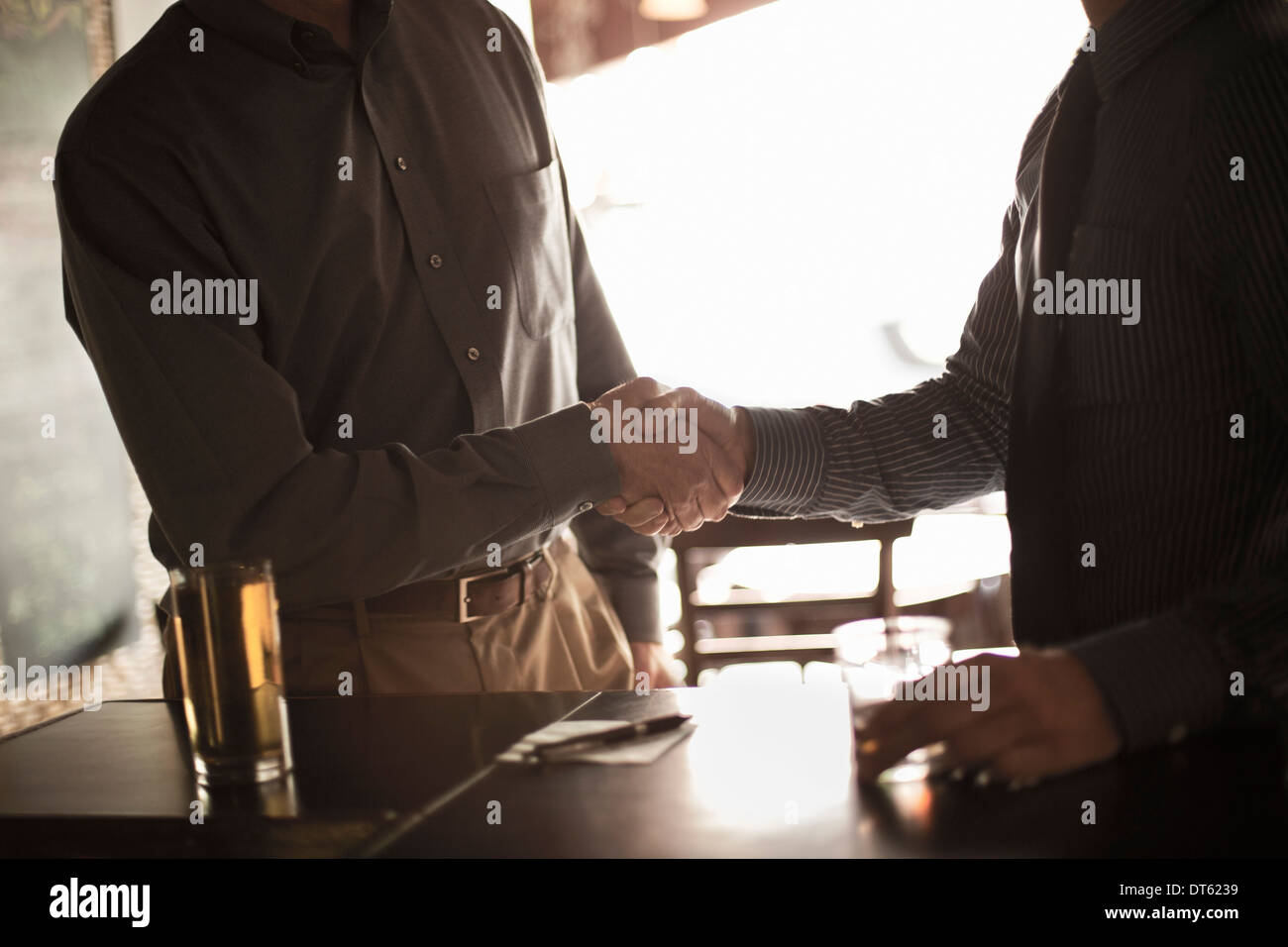 Two businessmen shaking hands in wine bar Stock Photo - Alamy