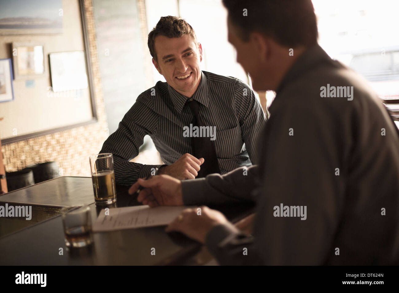 Business partners signing contract in a wine bar Stock Photo - Alamy