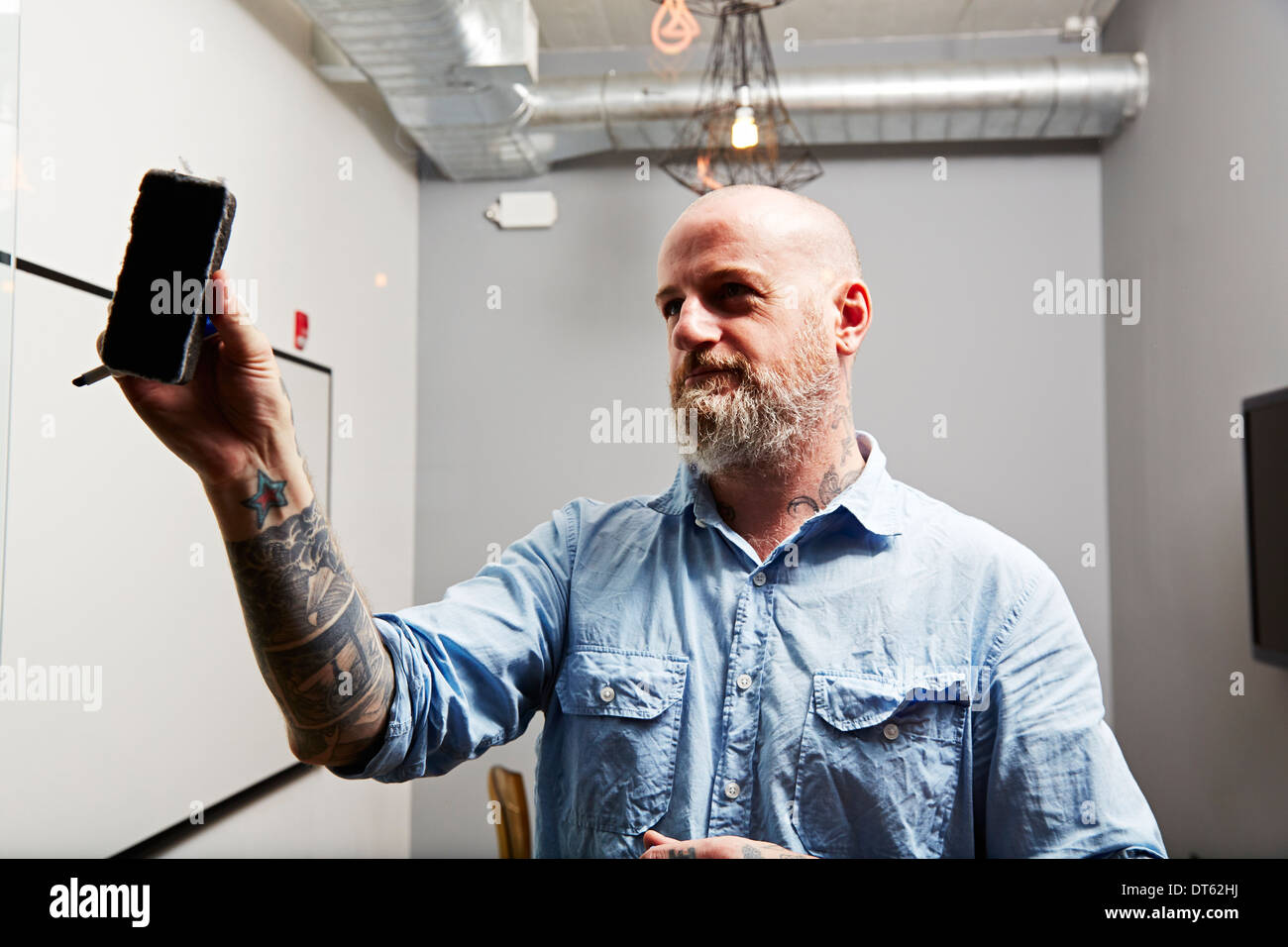 Mature man using whiteboard eraser Stock Photo - Alamy