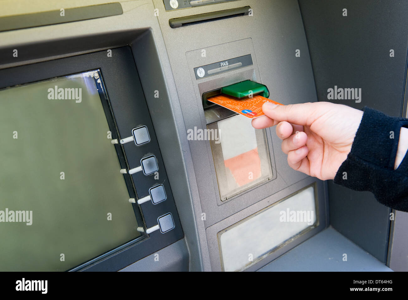 A woman is putting her bank card into an ATM machine to withdraw cash ...