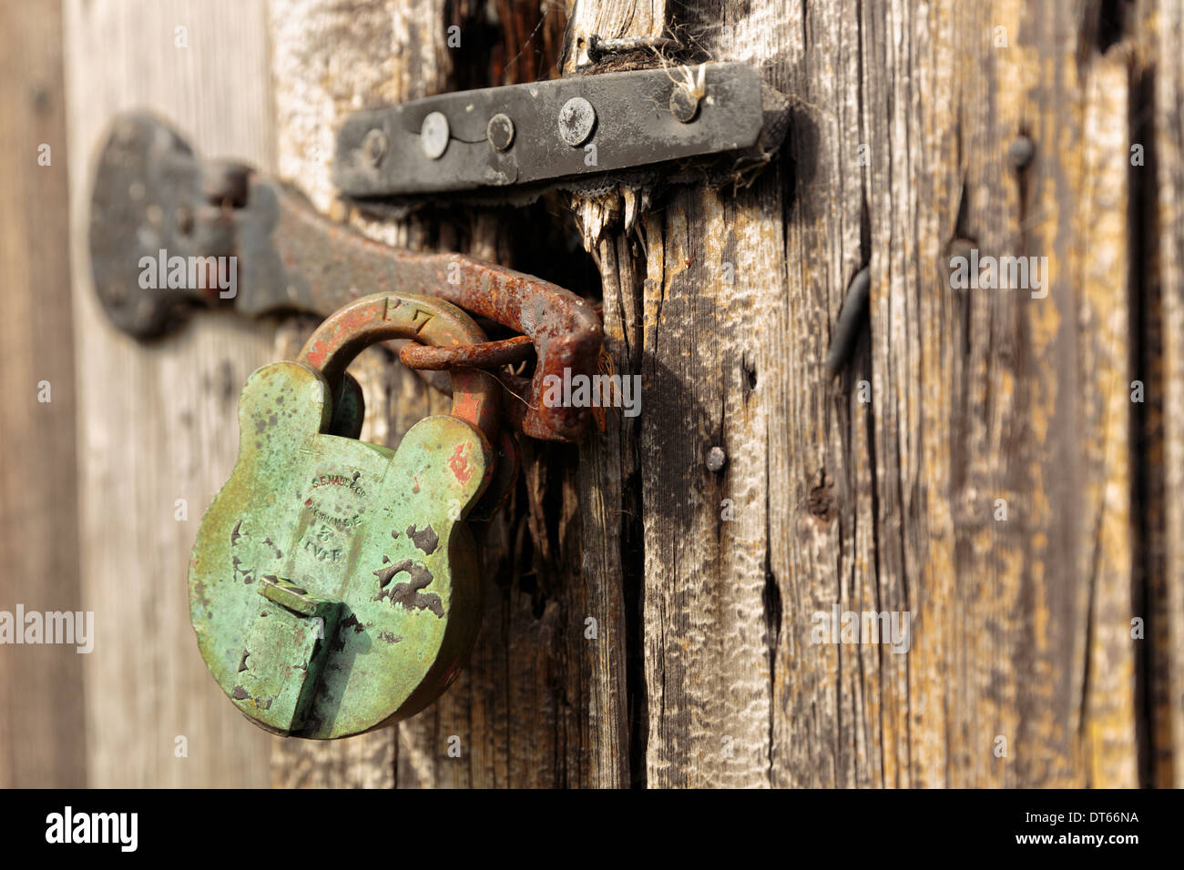 Padlock and rusting latch on outside wooden door Stock Photo - Alamy