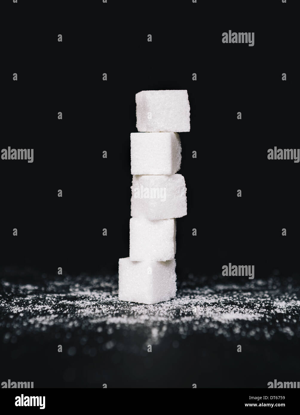 Stack of sugar cubes, balancing one on top the other, on black backdrop ...