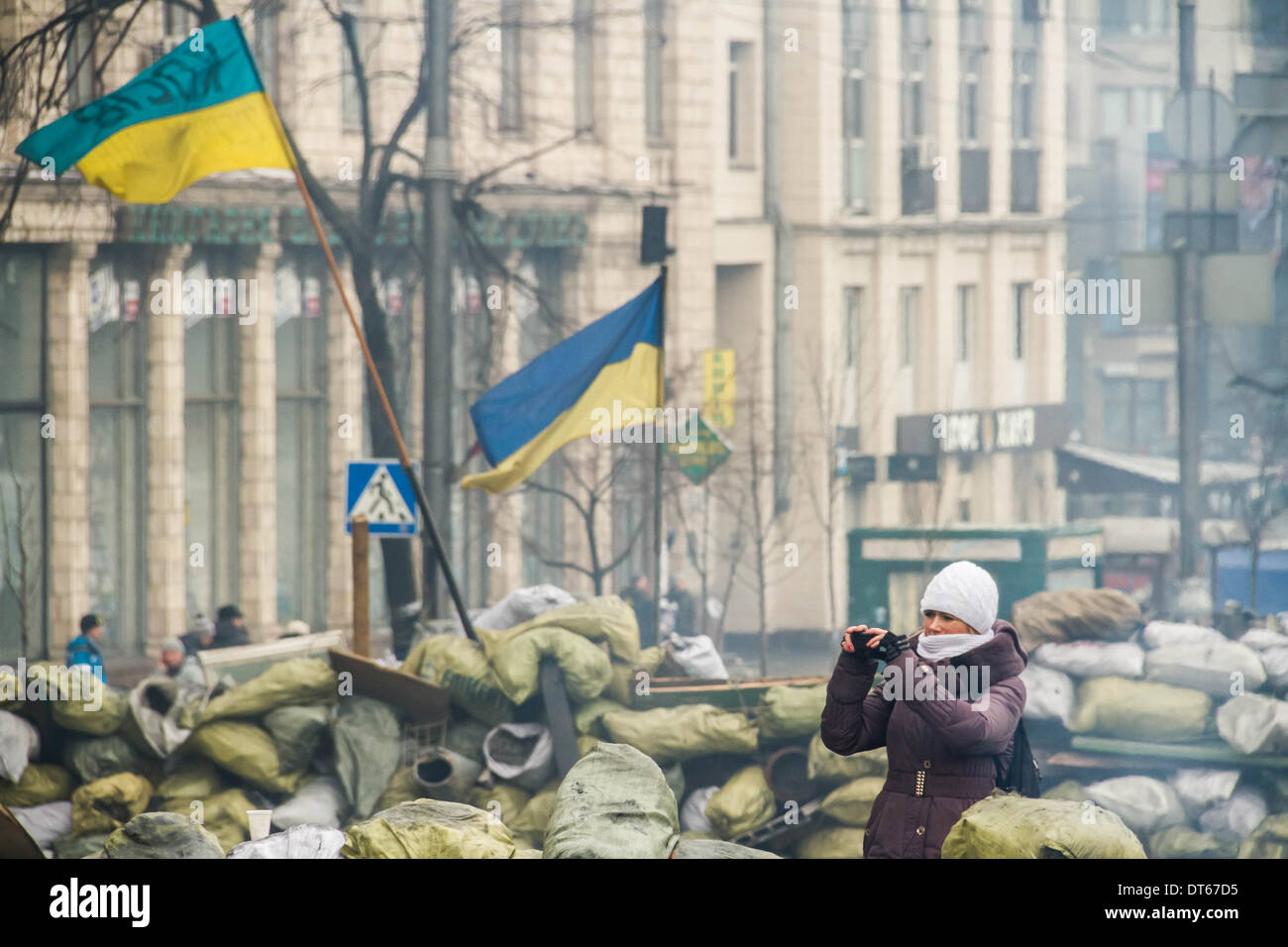 A local lady takes a photo of the riot police line over the barricades ...