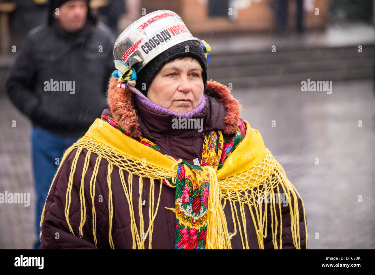 A Euromaidan supporter with cooking pot helmet by the Euromaidan stage ...