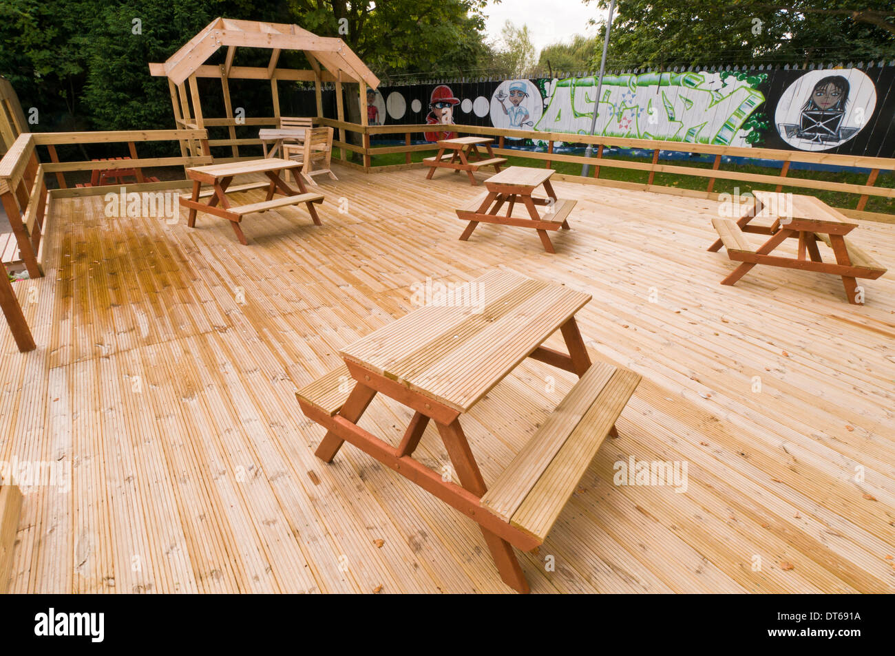 Timber decked seating area with picnic tables Stock Photo - Alamy