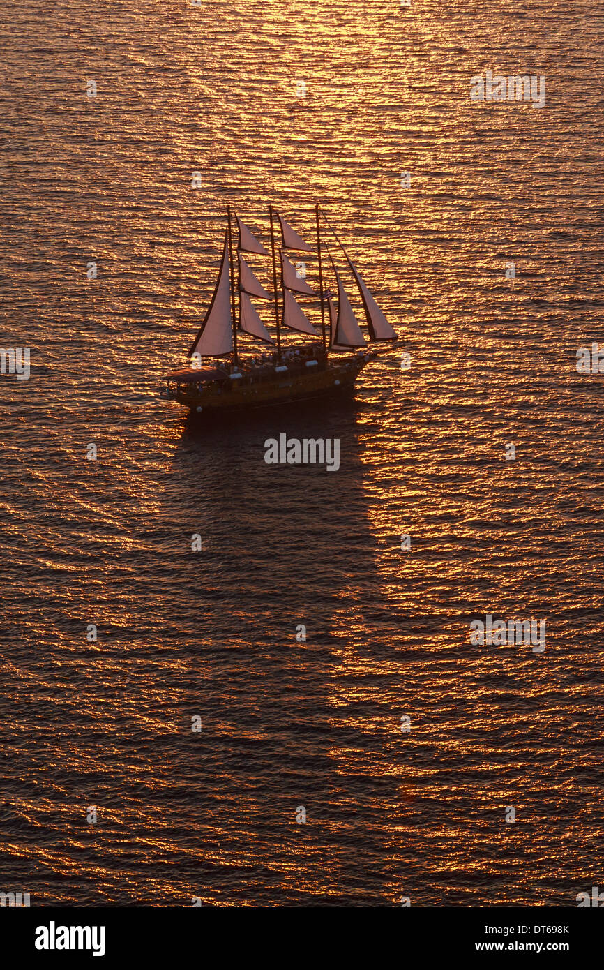 A three-masted sailing ship with full sail on the Aegean Sea at sunset ...