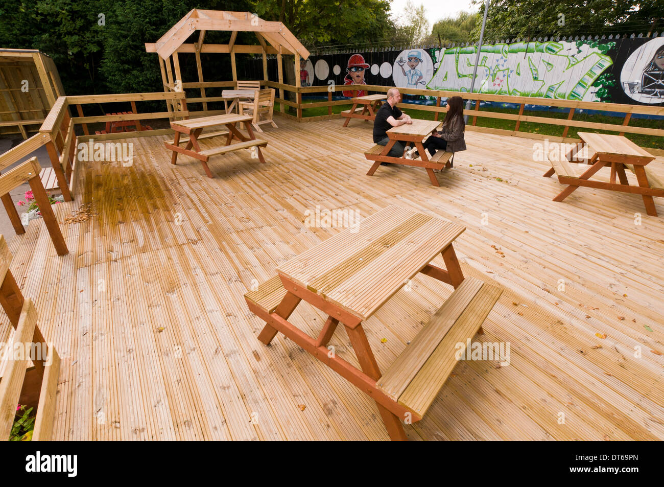 Two people talking on a decked seating area Stock Photo - Alamy