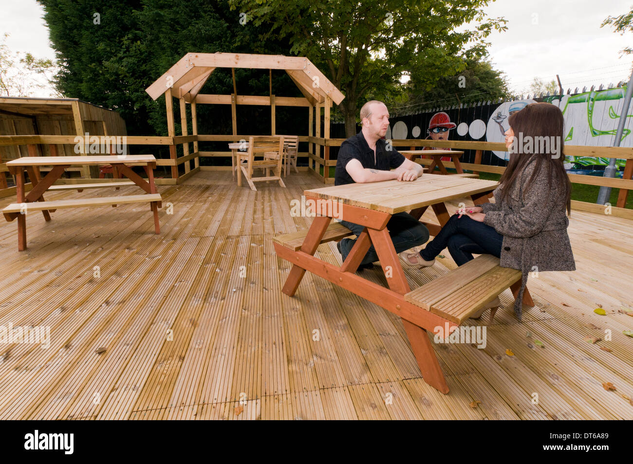 Two people talking on a decked seating area Stock Photo - Alamy