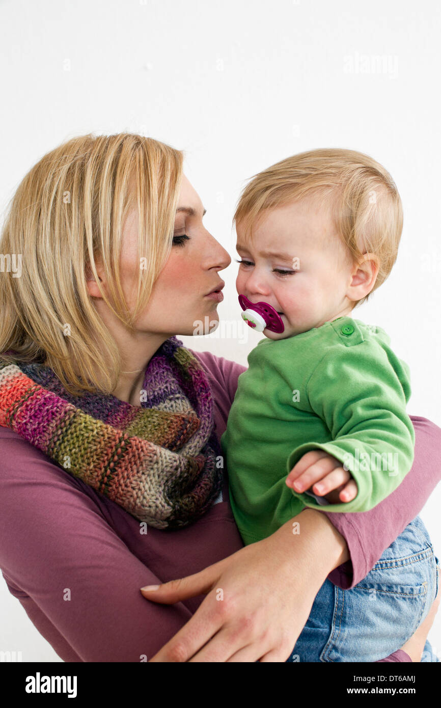 Studio portrait of mother trying to soothe baby daughter Stock Photo ...