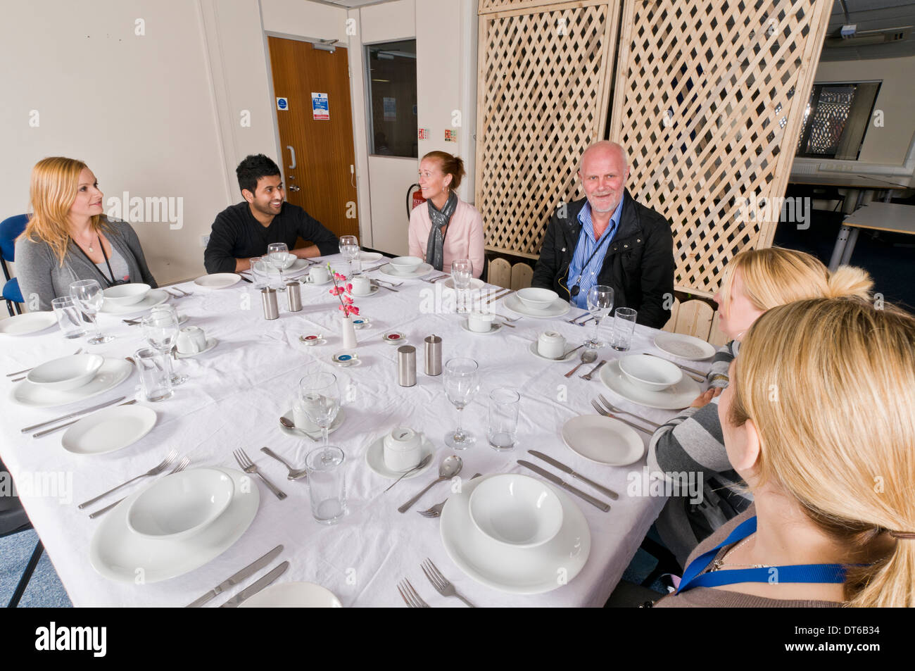 Group of people sat around a dinner table ordering food Stock Photo - Alamy