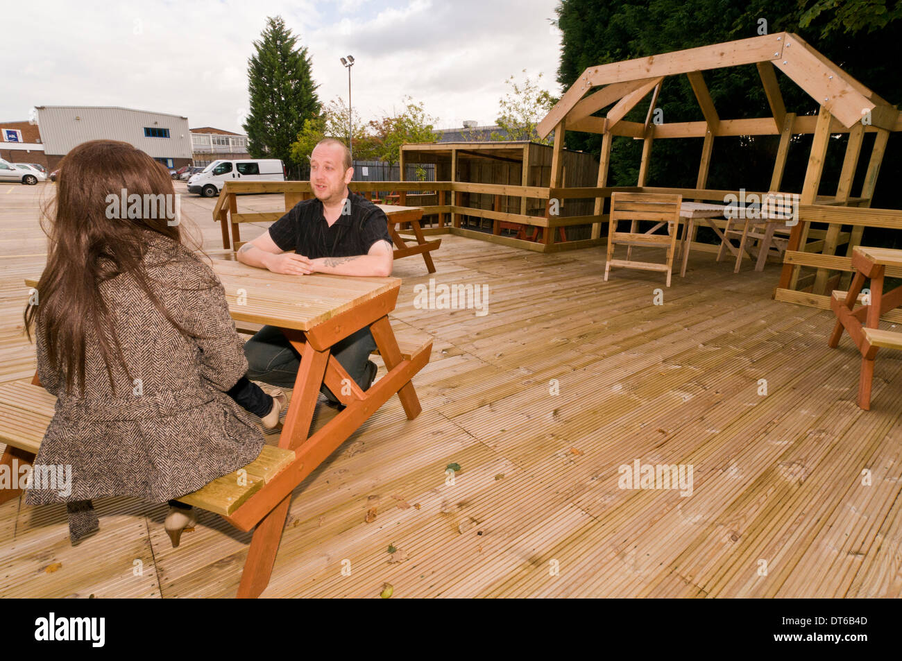 Two people talking on a decked seating area Stock Photo - Alamy