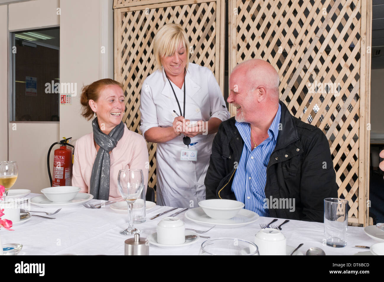 Group of people sat around a dinner table ordering food Stock Photo - Alamy