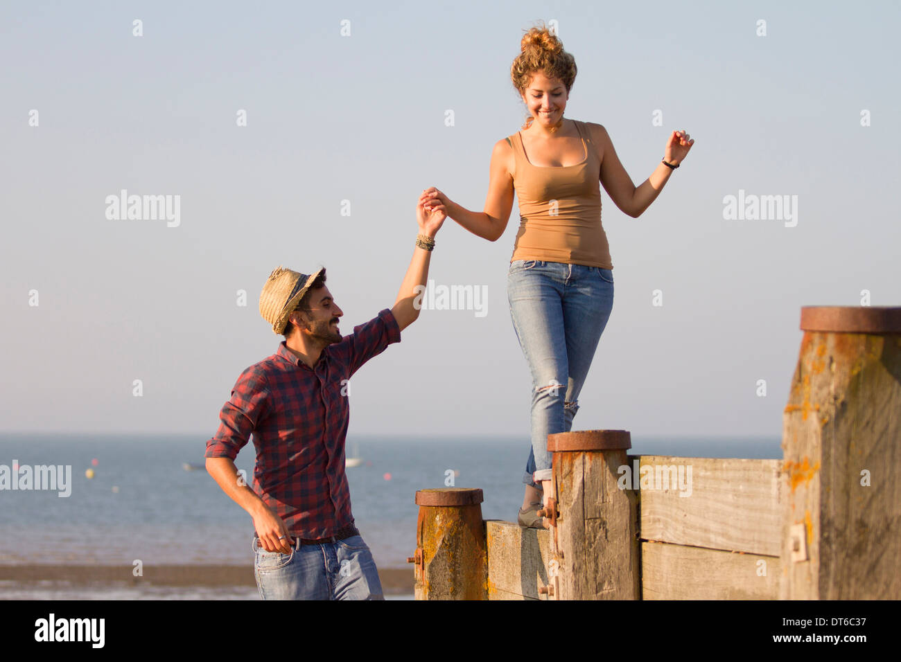 Young woman balancing on groynes holding man's hand Stock Photo - Alamy
