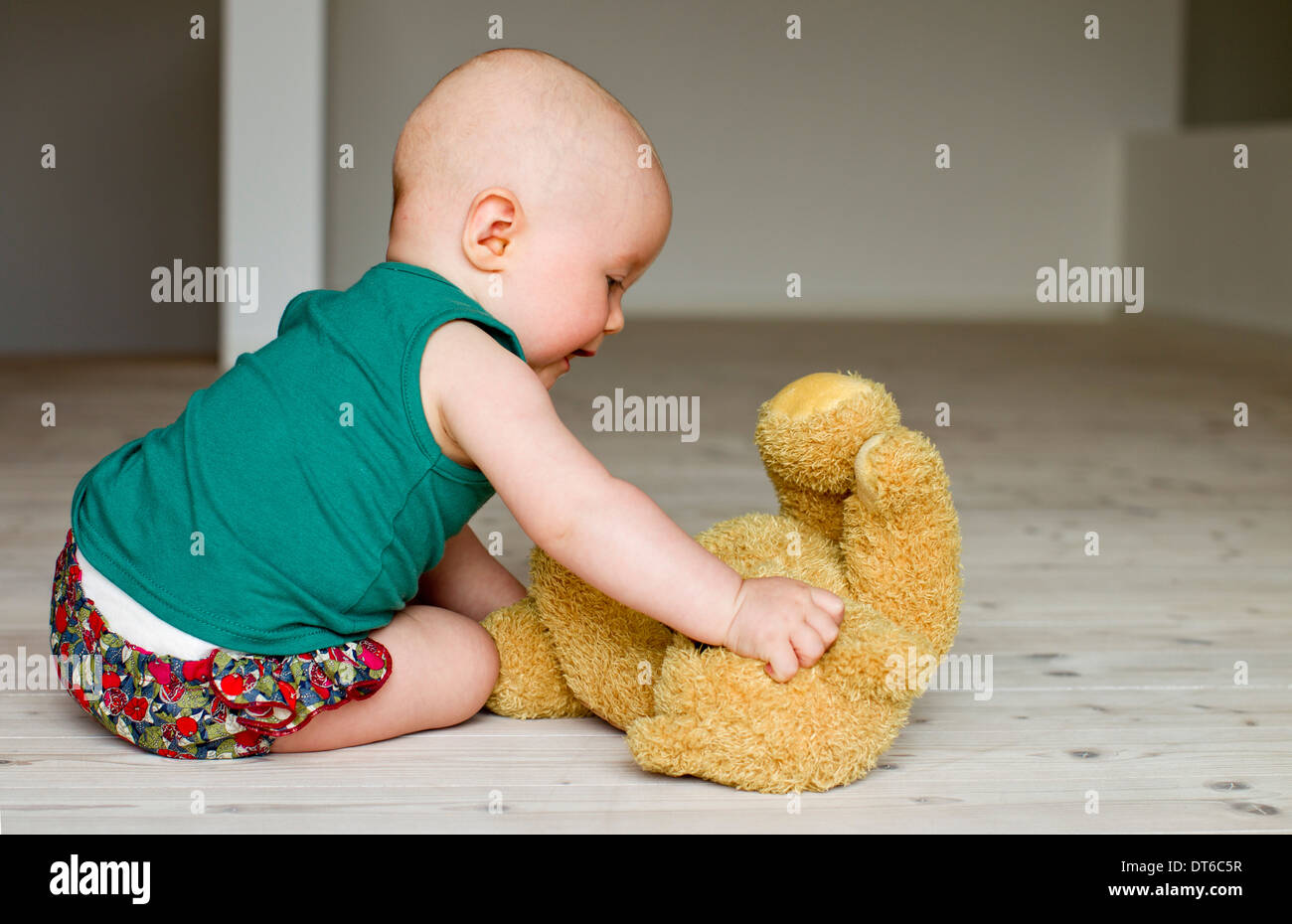 Baby girl playing with teddy bear on floor Stock Photo - Alamy