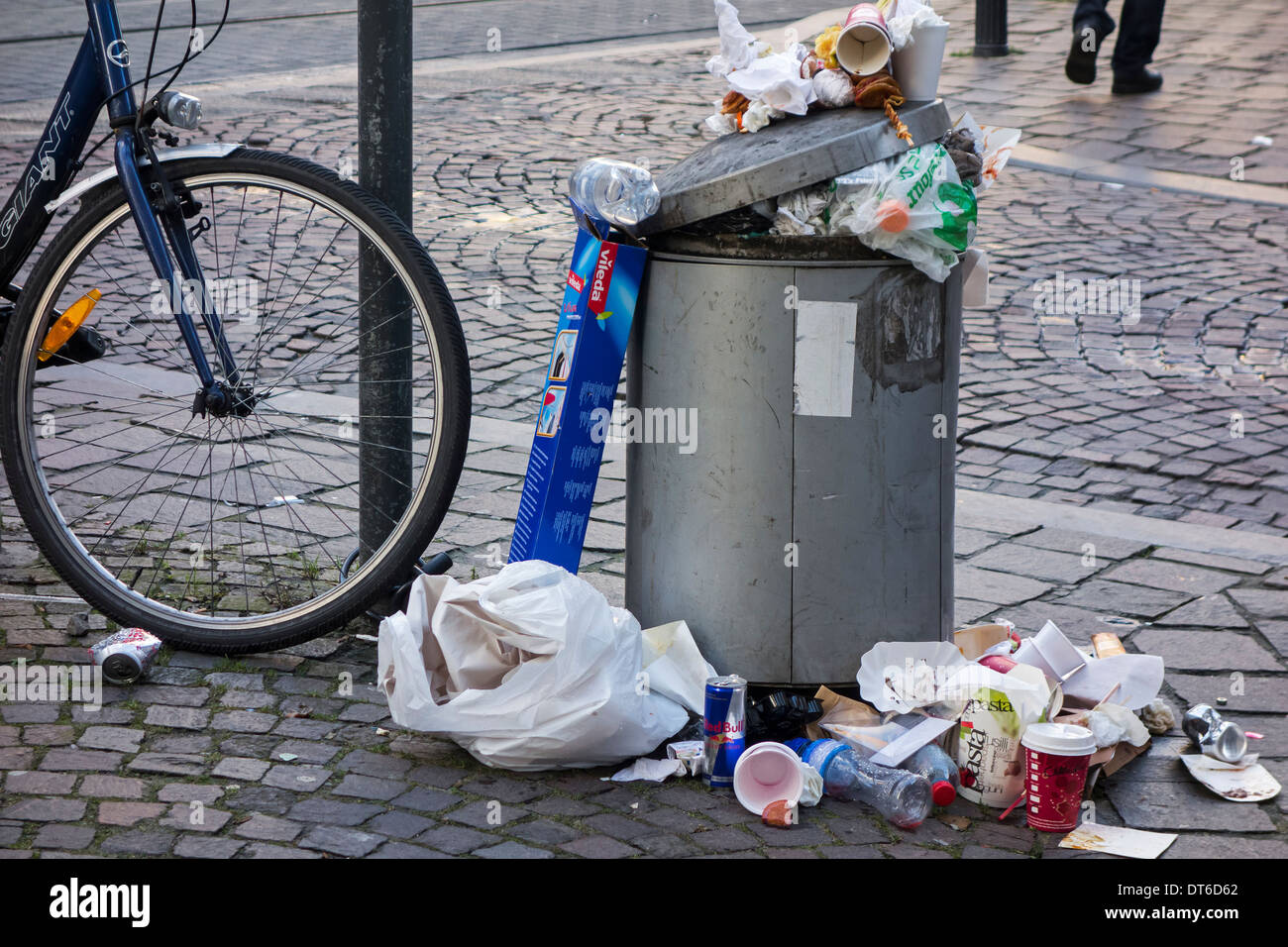 Overfull rubbish bin with trash around and garbage piled on top in city ...