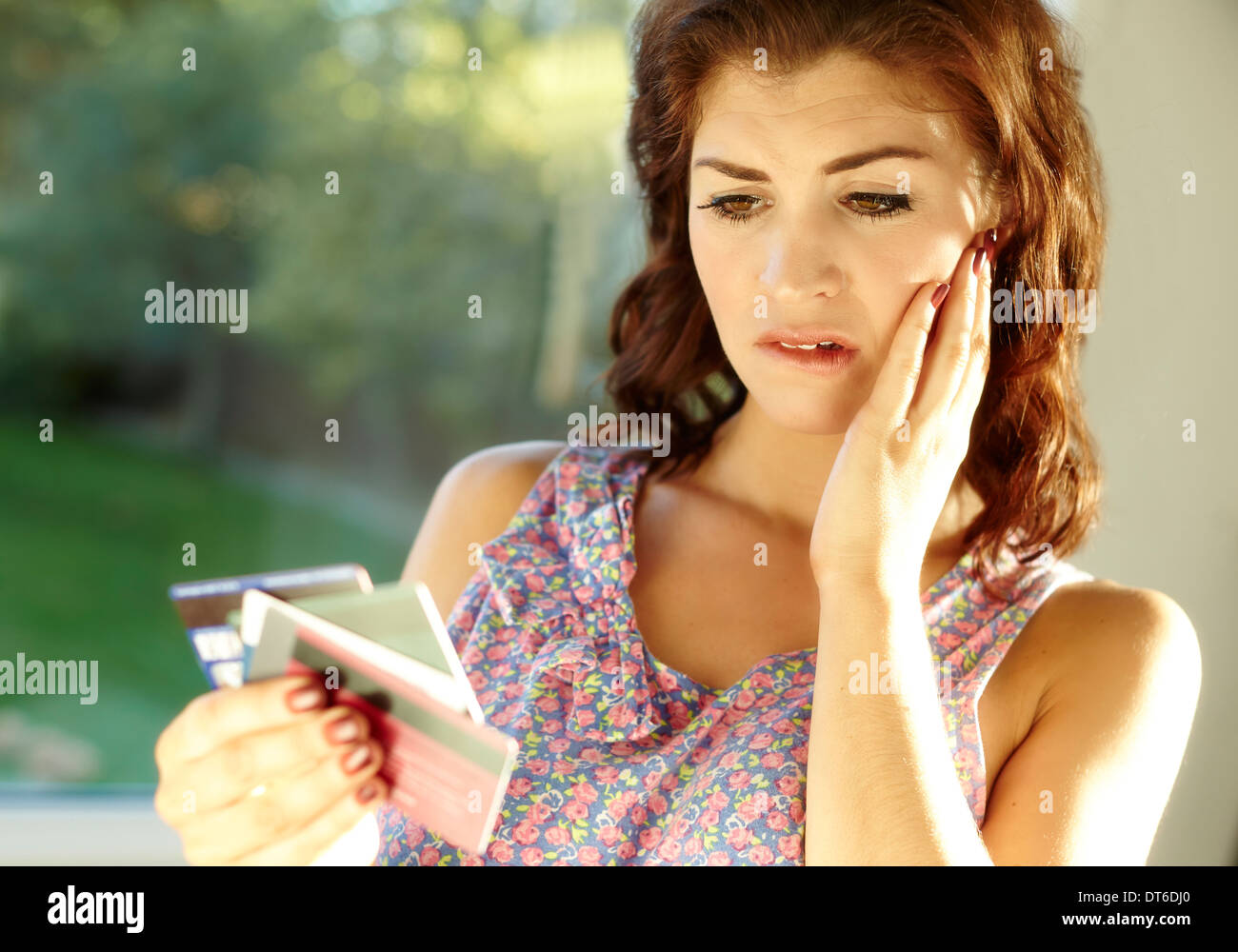 Girl looking concerned holding credit cards Stock Photo - Alamy
