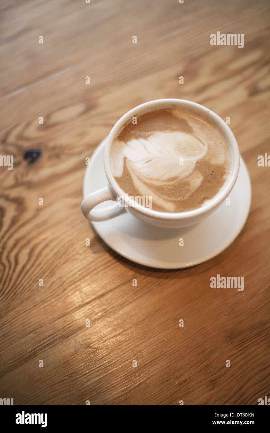 A cup of frothy coffee in a white china cup with a saucer. Cappuchino ...