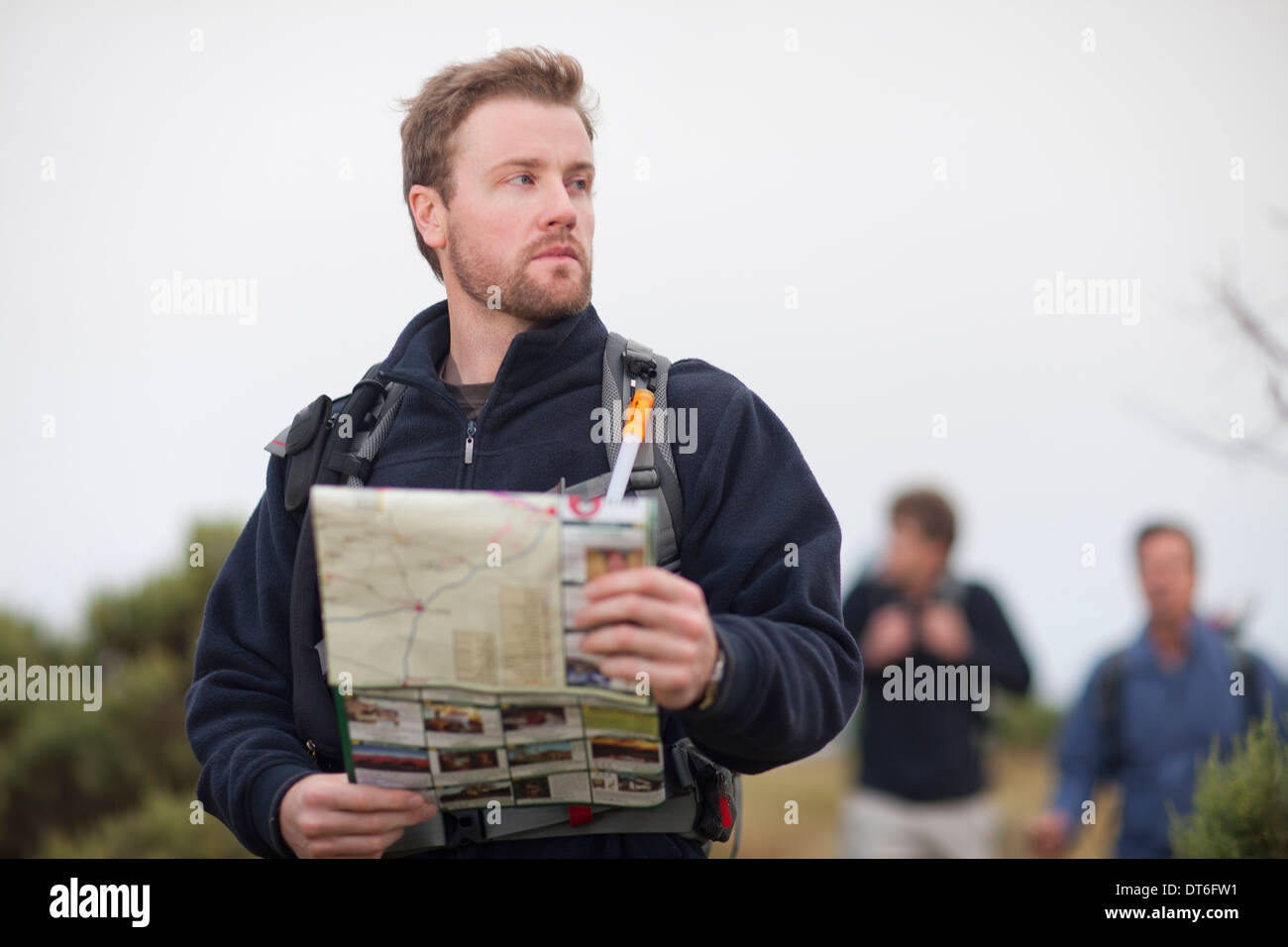 Three men hiking with backpacks and map Stock Photo - Alamy