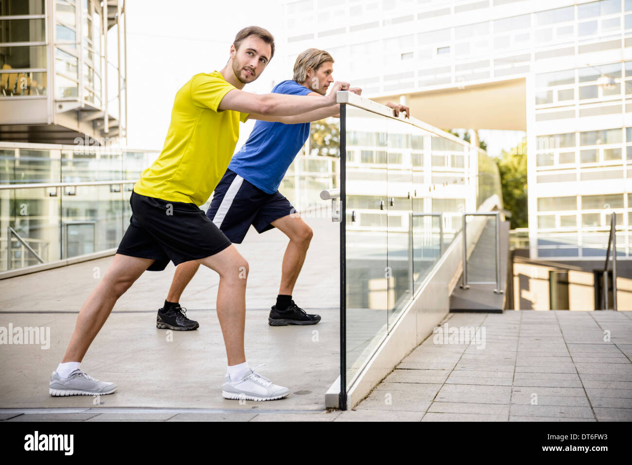 Two men leaning and stretching legs Stock Photo - Alamy