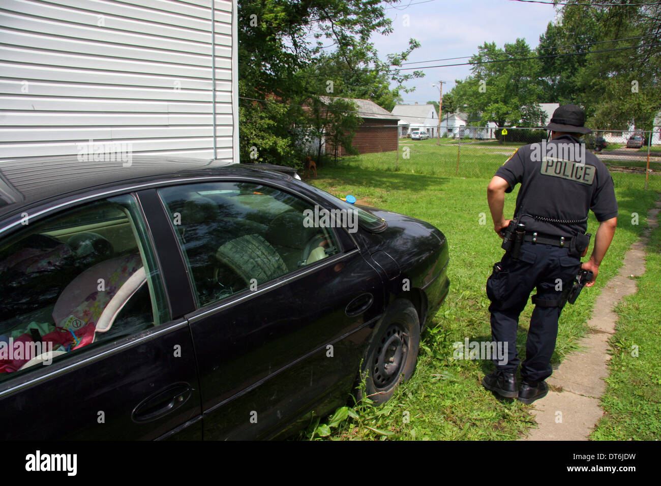 A Detroit Police Department Narcs officer searches the rear of a house ...