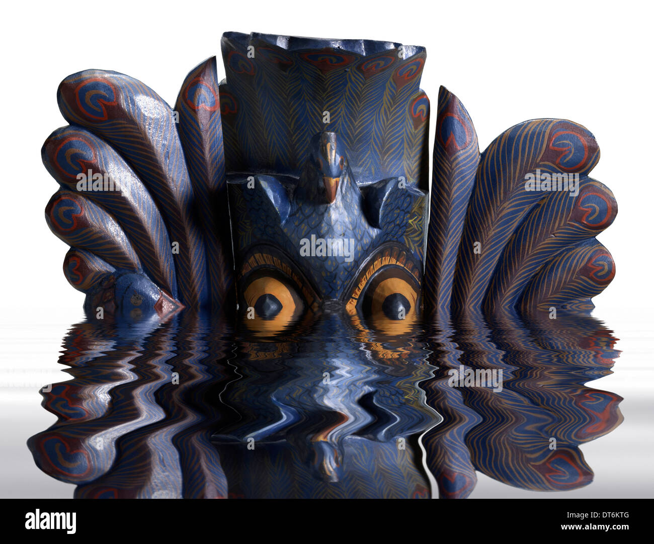 sinking colorful painted indigenous wooden mask on reflective water ...