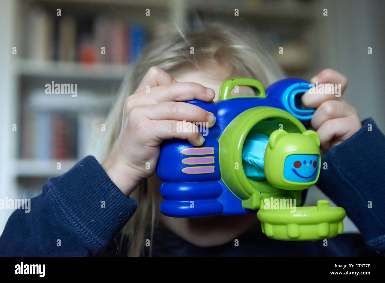 Portrait of Child little blond girl playing with plastic toy camera ...