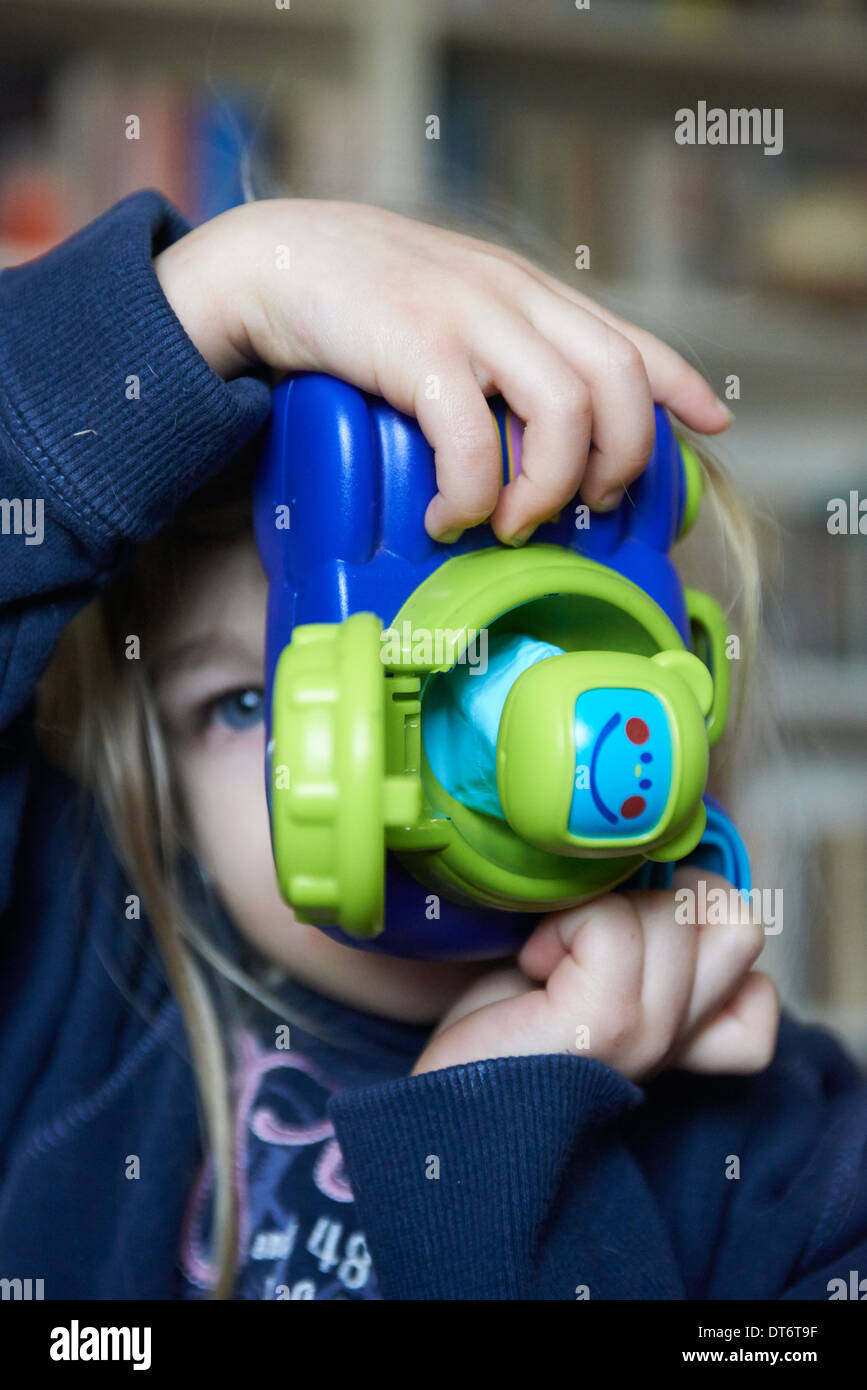 Portrait of Child little blond girl playing with plastic toy camera ...