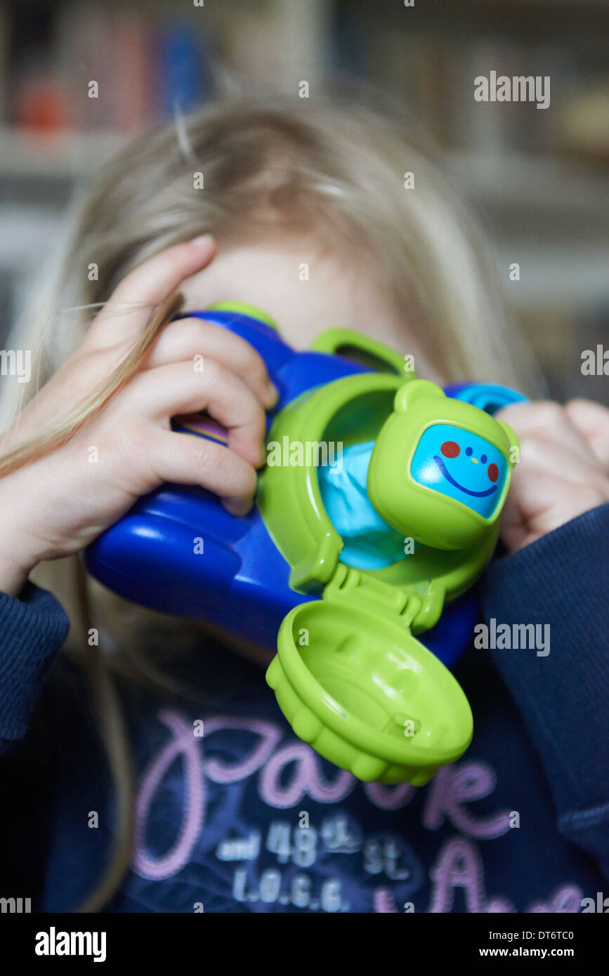 Portrait of Child little blond girl playing with plastic toy camera ...