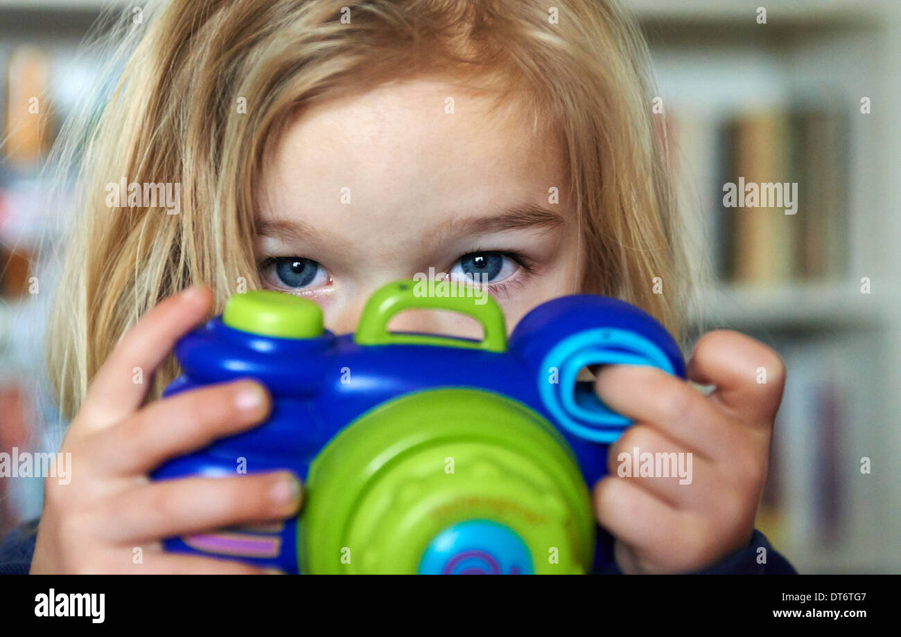 Portrait of Child little blond girl playing with plastic toy camera ...