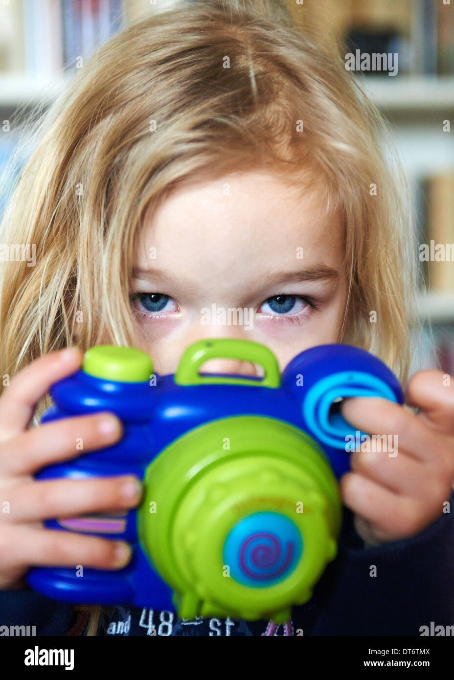 Portrait of Child little blond girl playing with plastic toy camera ...