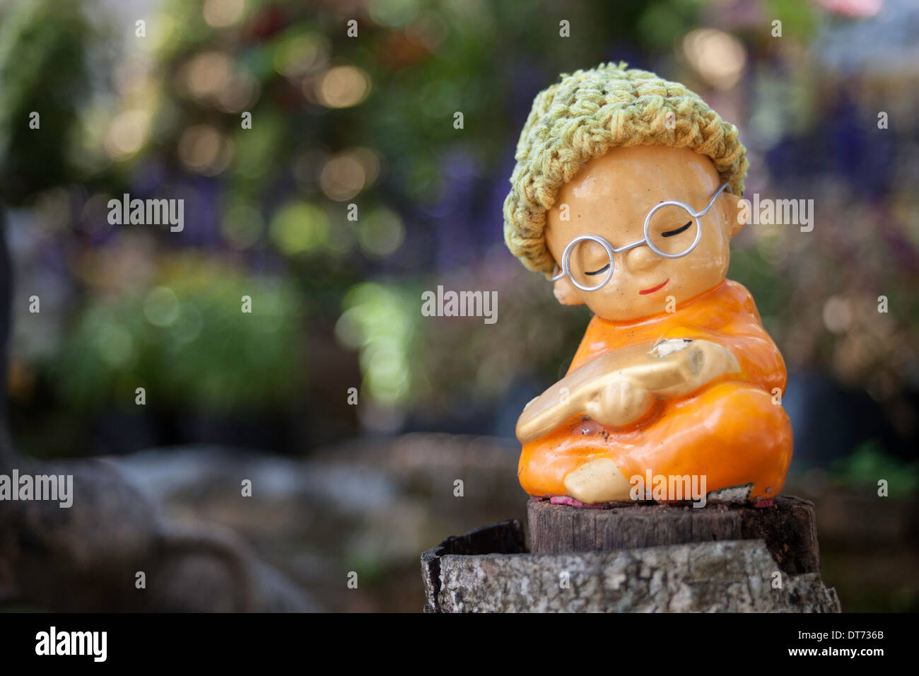 miniature doll monk with glasses sitting on a stump Stock Photo - Alamy
