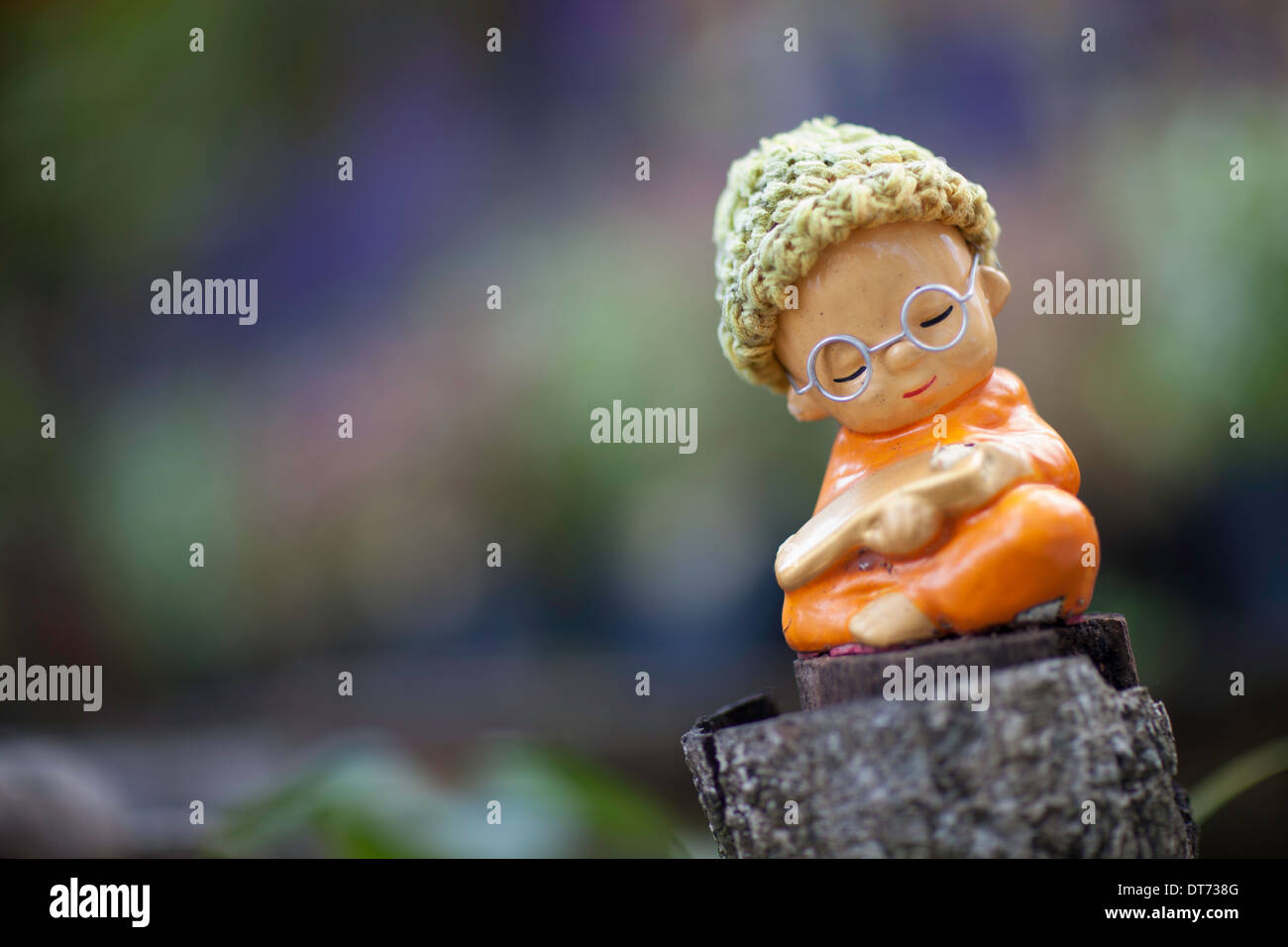 miniature doll monk with glasses sitting on a stump Stock Photo - Alamy