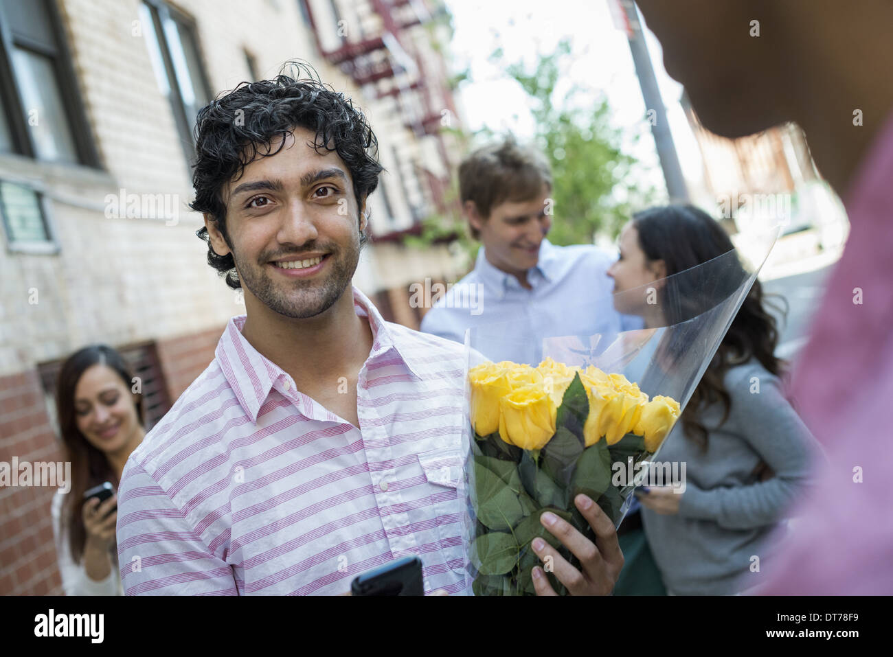 New York city street. A group of five people, one man carrying a bunch ...