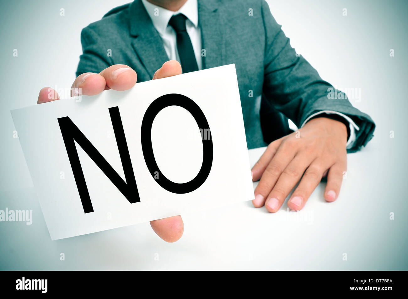 man wearing a suit sitting in a table showing a signboard with the word ...