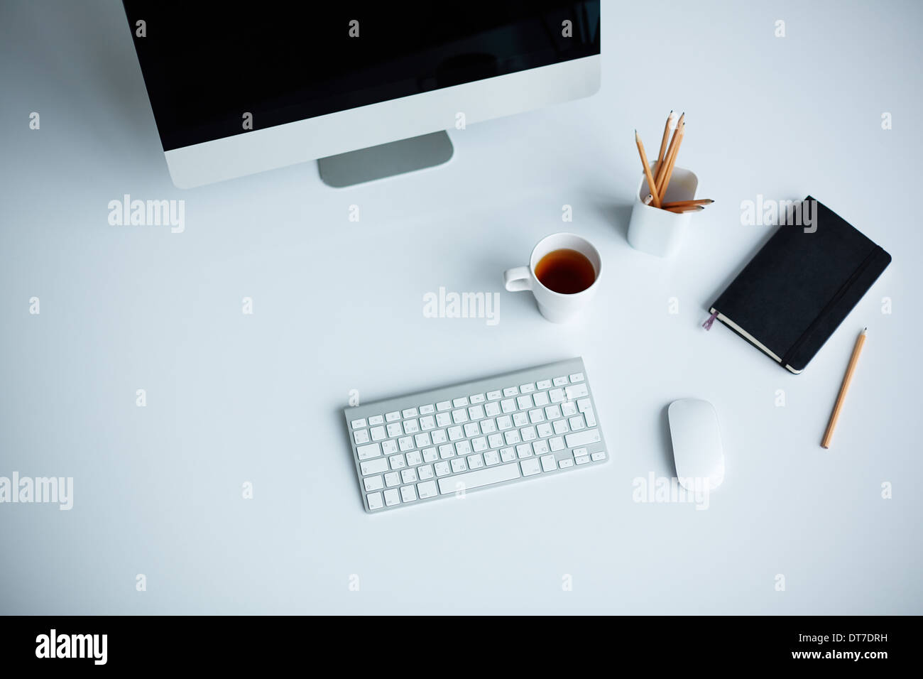Image of cup of tea, monitor, keypad, pencils in glass, notebook and ...