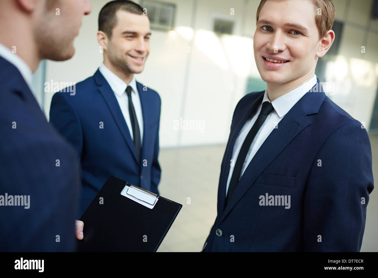 Young emploee looking at camera with his colleagues near by Stock Photo ...