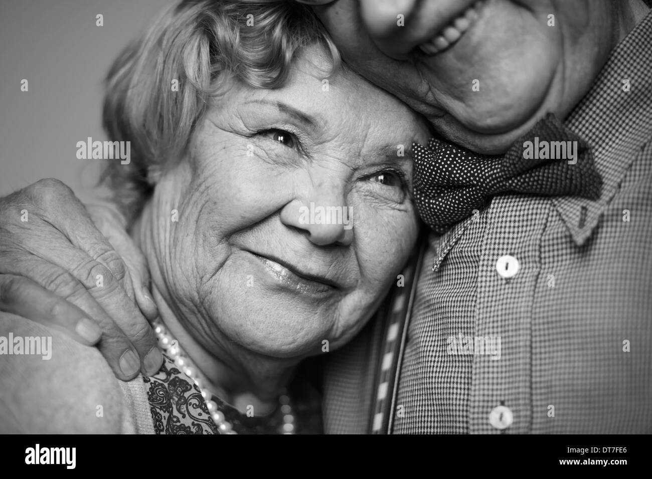Black-and-white image of senior female being embraced by her husband ...