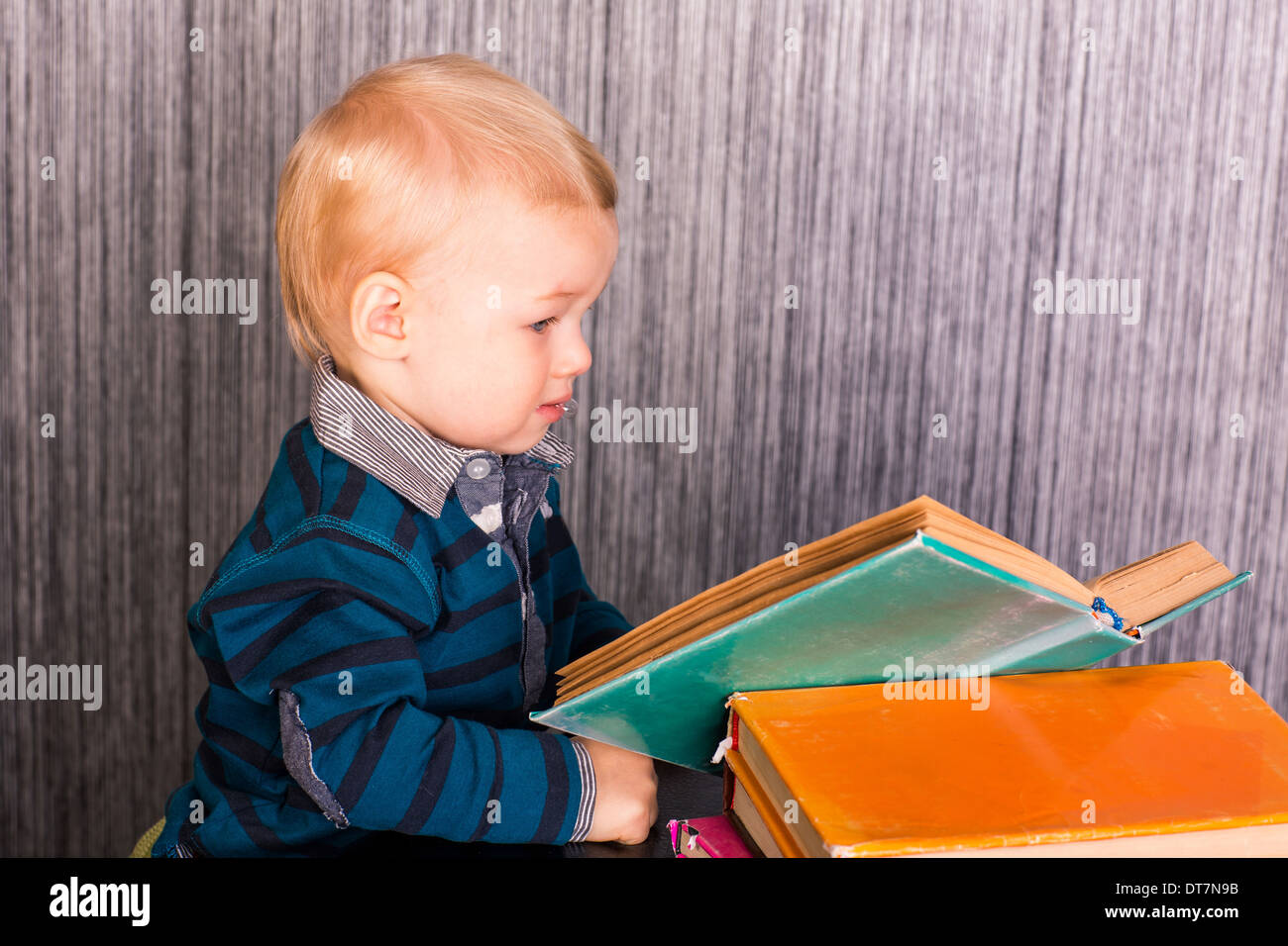 Adorable curious baby boy studying a pile of books indoor Stock Photo ...